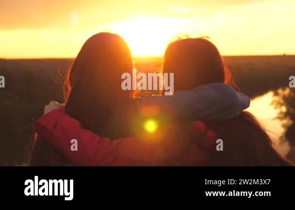 Girls hug and watch the sunset. The traveler is a hiking colleague ...