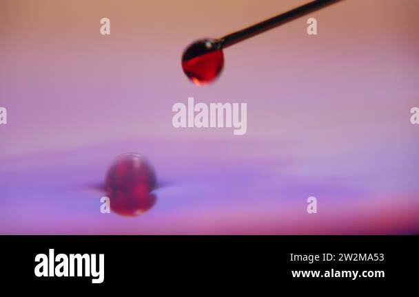 Small drops of red blood falling from a metallic needle on surface full ...