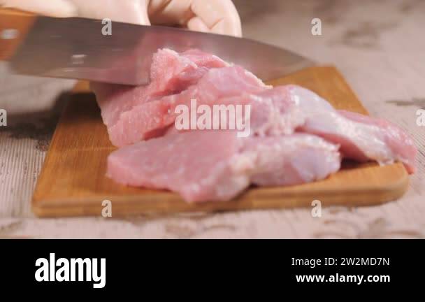 Metal knife cuts up the meat. Cutting meat on a wooden Board. Piece of ...