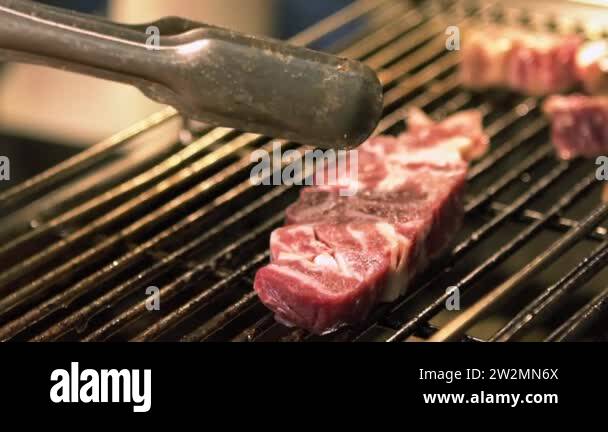 Slow motion of a Vendor cooking a beef meat on steel grill in Asian ...