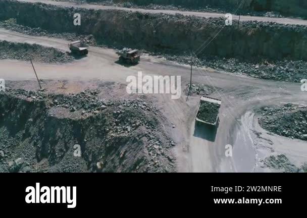 Mining dump trucks in large granite open pit mine. Loaded truck rides ...