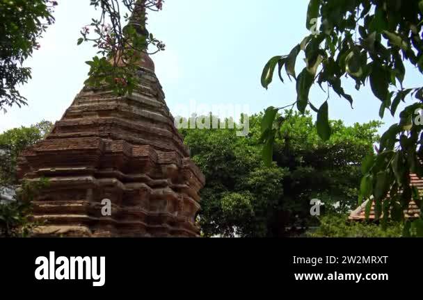 4K A massive brick centuries old Chedi at park with green trees of ...
