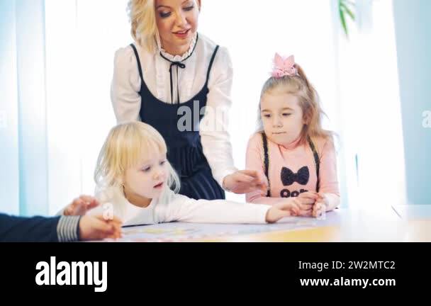 Children with their teacher together at round table in class. Little ...