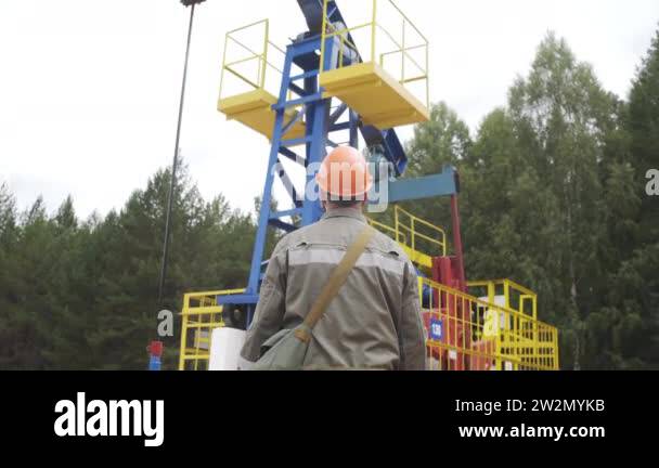 Oil field technical worker standing with his back to camera and in ...