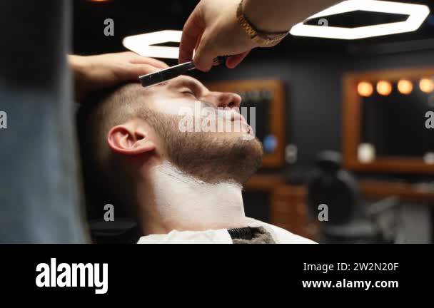 Professional barber shaves customer beard with straight razor. Beard ...