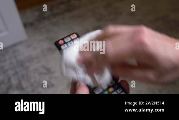 A closeup view of a man cleaning his television remote control with a ...