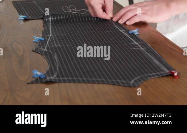 hands of a seamstress sewing with basting thread a jacket of high ...