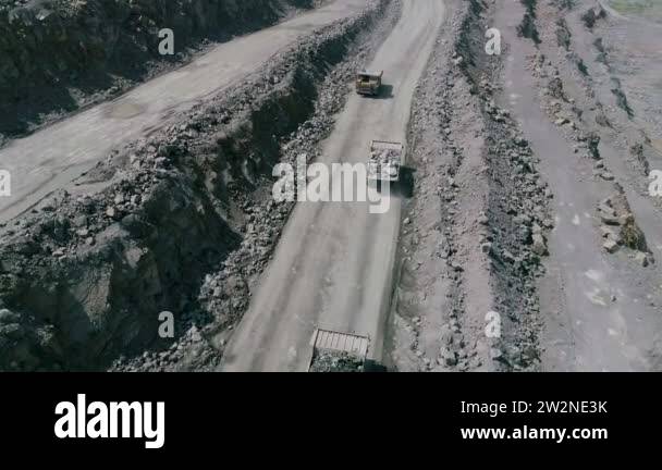 Mining dump trucks in large granite open pit mine. Loaded truck rides ...