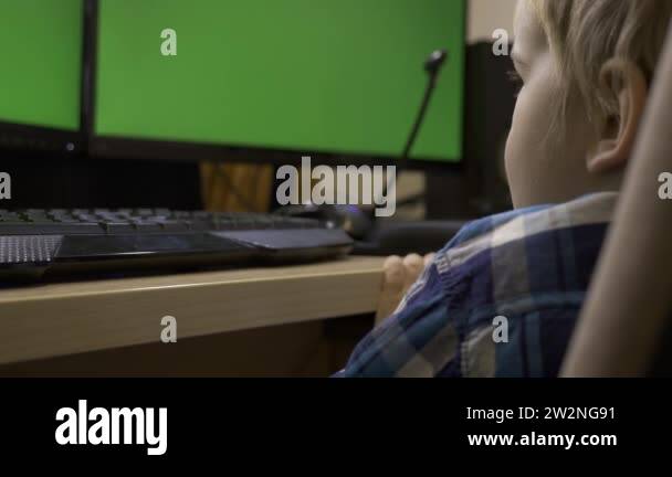 Little Child Sits Watching in front of Green Screen Monitors ...