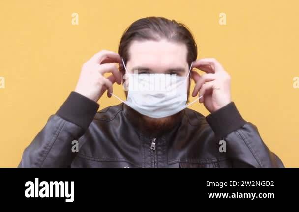 man puts on and removes a disposable mask to protect against the ...