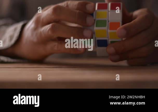 Close up hands of businessman solving rubik's cube puzzle on the desk ...