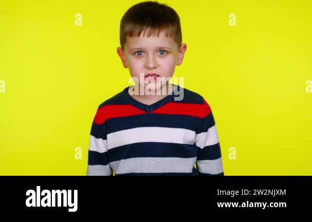 Confused little boy growls at the camera on a yellow background with ...