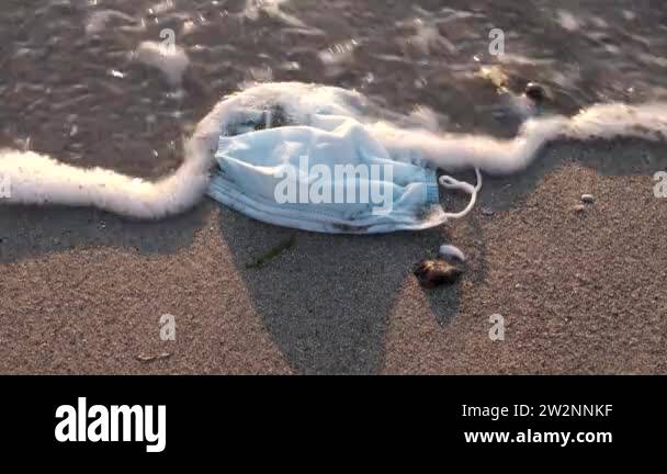 Disposable face masks and plastic debris on the beach in surf zone ...