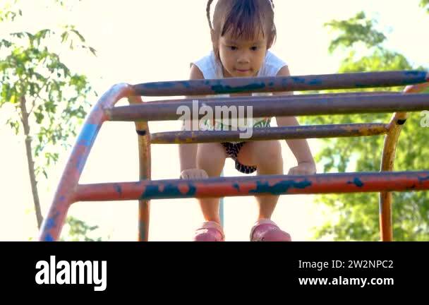Happy little girl having fun playing on monkey bars at a playground ...