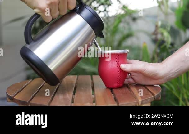 Man making yerba mate tea. Close up pouring hot water into traditional ...