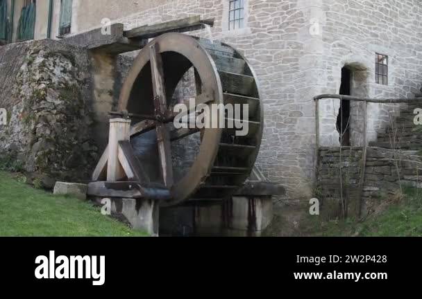 Rotating old wooden wheel of mill. Two children entering mill Stock ...