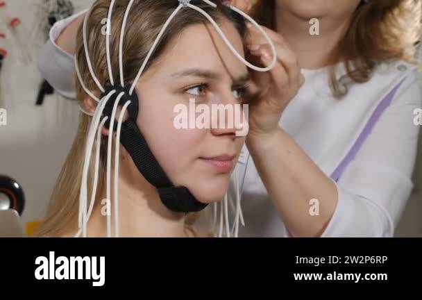 Doctor connecting electronic sensors with wires to female patient ...
