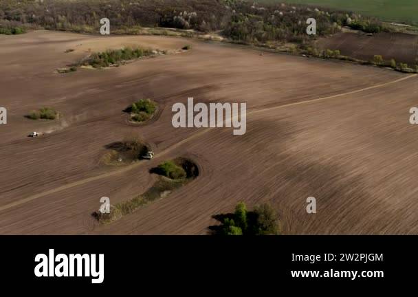 Aerial view large tractor cultivating a dry field. Top down aerial view ...