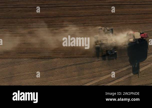 Top down aerial view of green tractor cultivating ground and seeding a ...