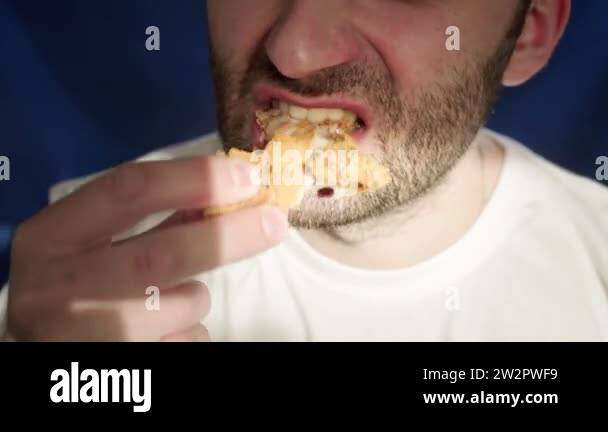 Close-up, a man with stubble eating a chicken leg. Holds nuggets with ...