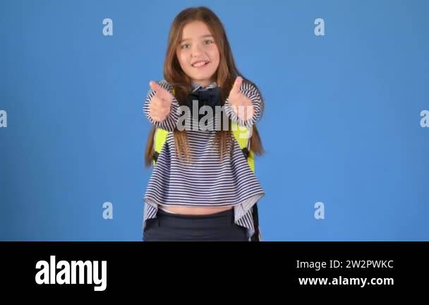 Happy smiling teenager girl jumping into the frame shows thumbs up on a ...