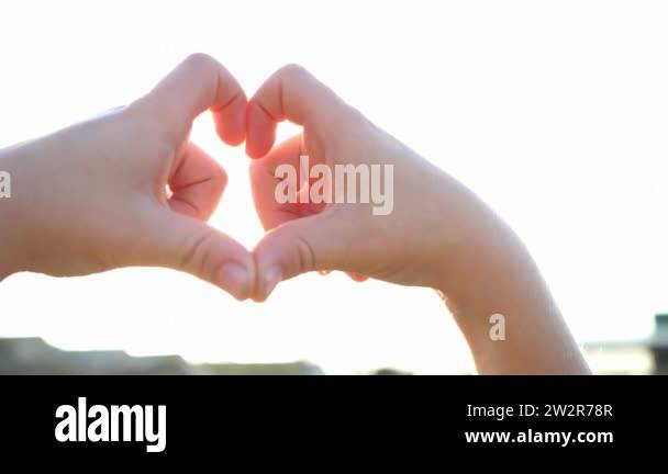 Kid making heart hands against the blue sky, child hands forming a ...