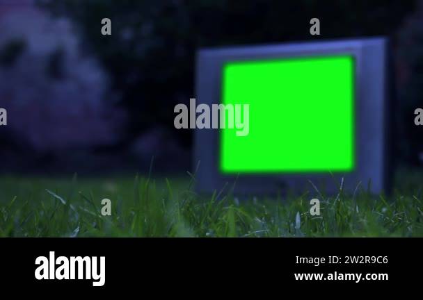 Old Blurred TV with Green Screen in Green Grass. Night Tone. You can ...