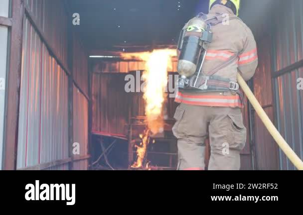 Rear view of Fireman wear fire protection suit walking into the fire ...