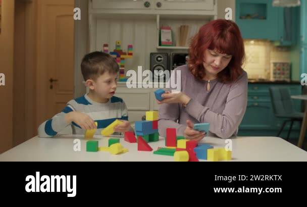 School boy with autism playing with color wooden blocks on the table ...
