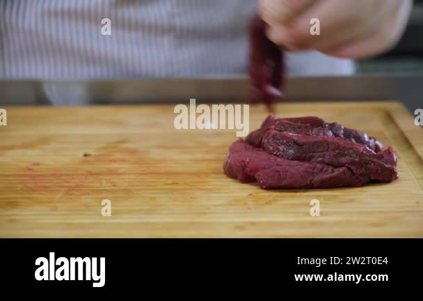 Chef cook in kitchen takes large fillet venison from an iron bowl and ...