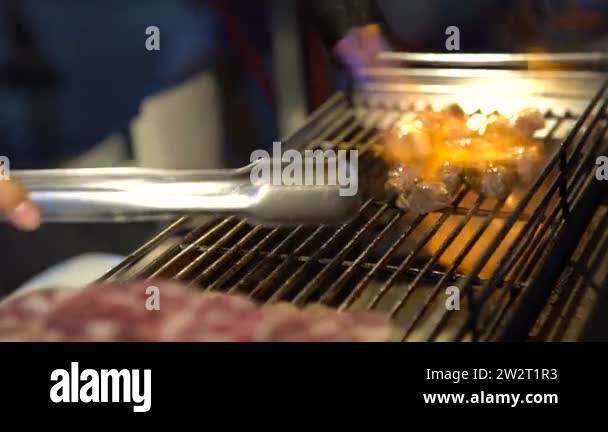 4k Vendor cooking a beef meat bits with blowtorch on steel grill in ...