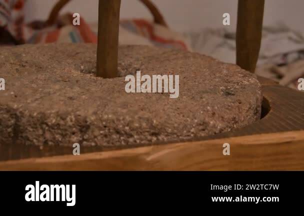 Grinding dry corn seed on an old millstone of medieval hand-driven ...