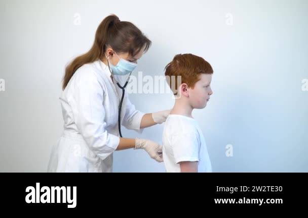 Female doctor pediatrician using a stethoscope listens to the lungs and ...