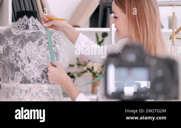 Beautiful tailor woman is filming a tutorial how to sew a delicate ...