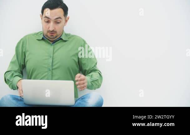 Isolated young man with surprised silly face sitting on the floor in ...