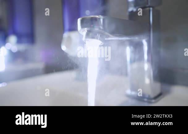 Hot tap water. Warm water flows from the tap in the bathroom ...