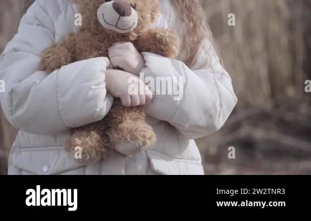 Close-up of unrecognizable little girl squeezing teddy bear in hands ...