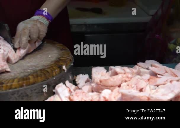 Slow motion stall vendor using ax for cutting piece of pork bacon on ...