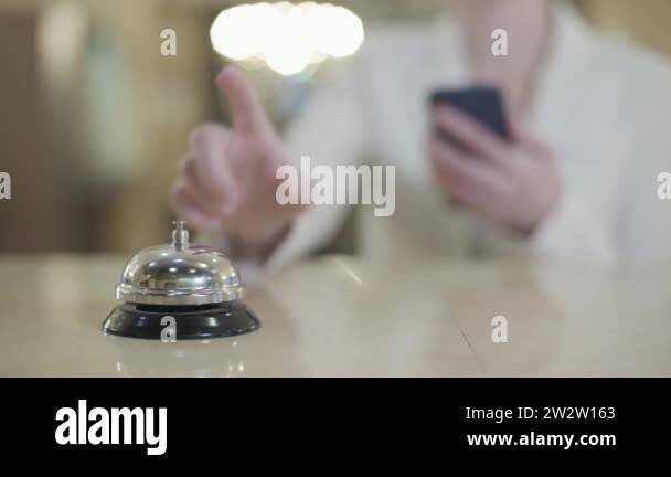 Blurred Caucasian woman with smartphone pressing hotel bell at ...
