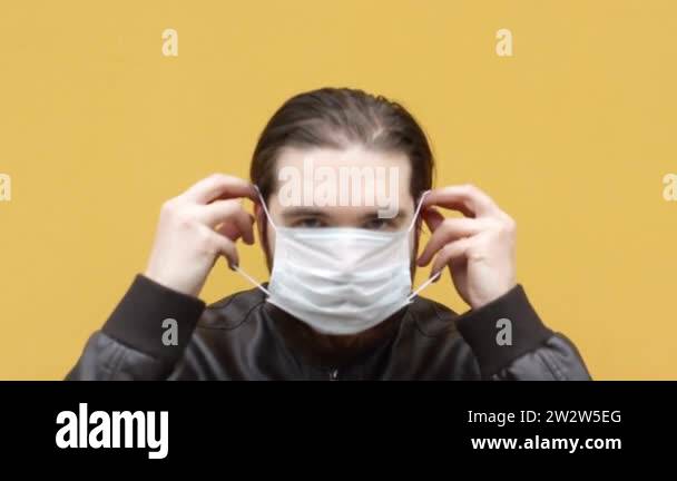 man puts on and removes a disposable mask to protect against the ...