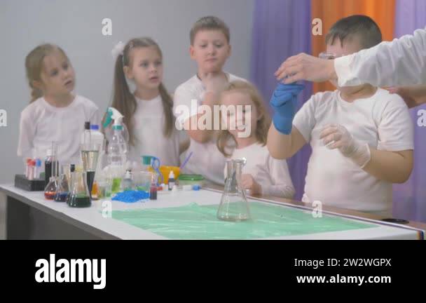 Chemical experiments for children. A woman adds ingredients to a flask ...