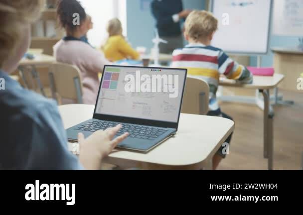 Elementary School Science Class: Over the Shoulder Little Boy Uses Laptop with Screen Showing ...