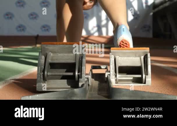 Back view of female athlete starting sprint on running track inside of ...