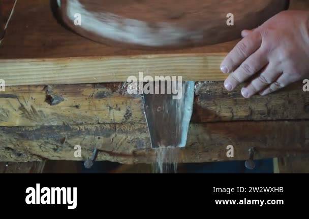 The ancient Quern stone hand mill with grain. The man grinds the grain ...