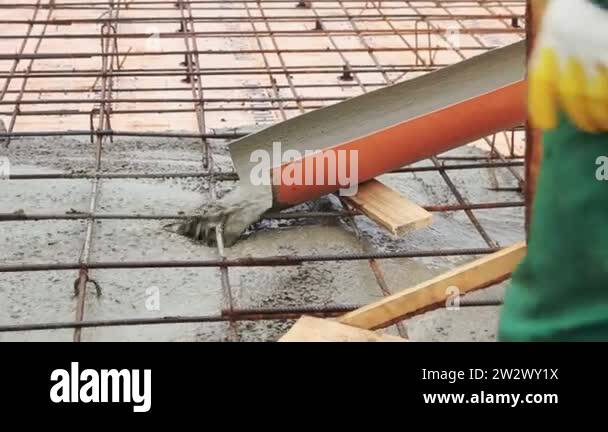 Pouring concrete mixture to the reinforcing mesh and a house foundation ...