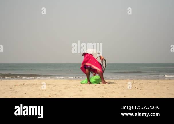 Arambol, India - February 2020. An Indian woman cleaner collects ...