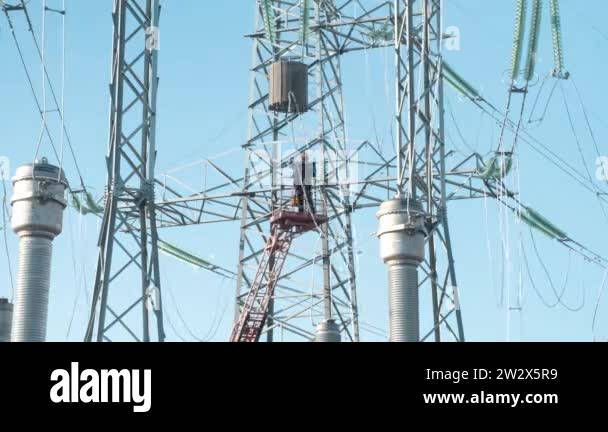 Electrician on a hydraulic lift on a high-voltage line of a substation ...