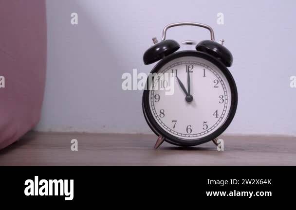 Alarm clock standing on the bedroom floor with eleven o'clock time on ...