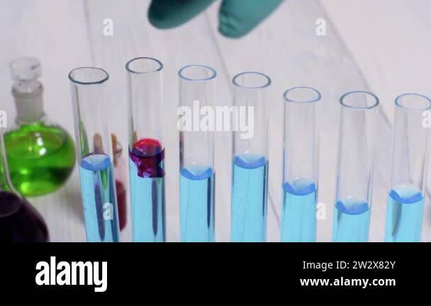 scientist pours the reagent into test tube for reaction testing in ...
