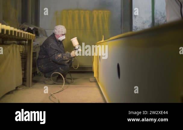 Worker in suit spray painting factory part. Clip. Painter ...